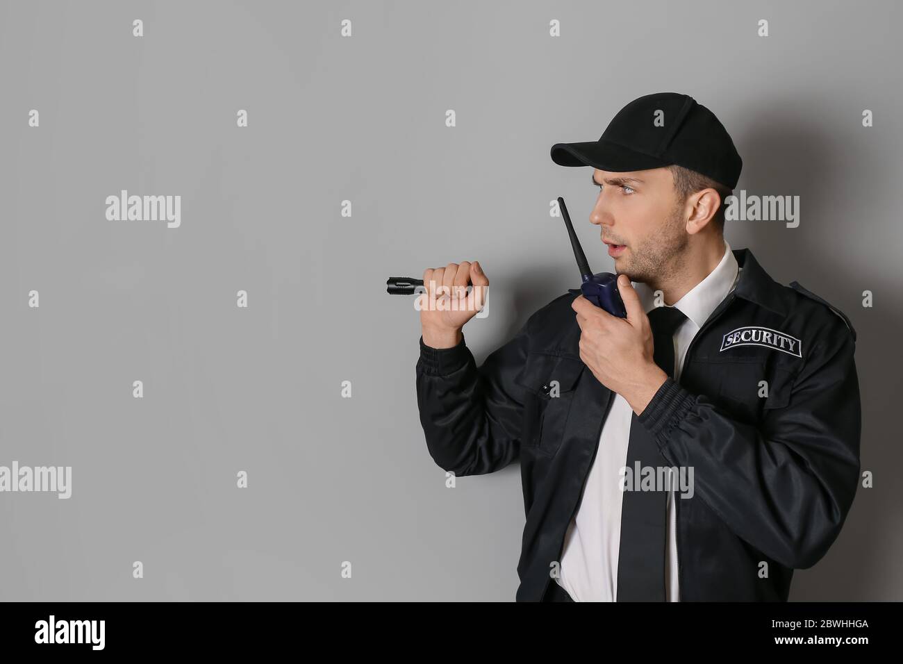 Male security guard with flashlight on grey background Stock Photo - Alamy