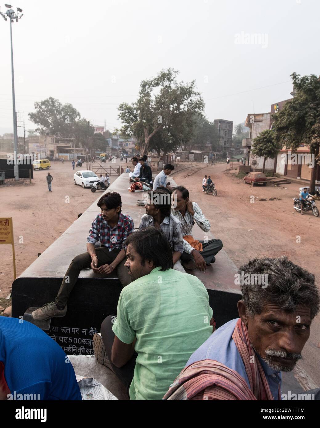 Men on top of overcrowded train passes through a small town in Madhya ...