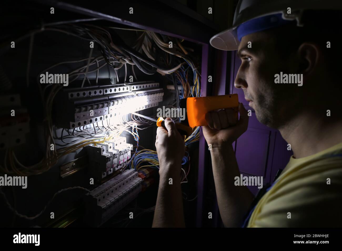 Male electrician with flashlight repairing distribution board Stock ...