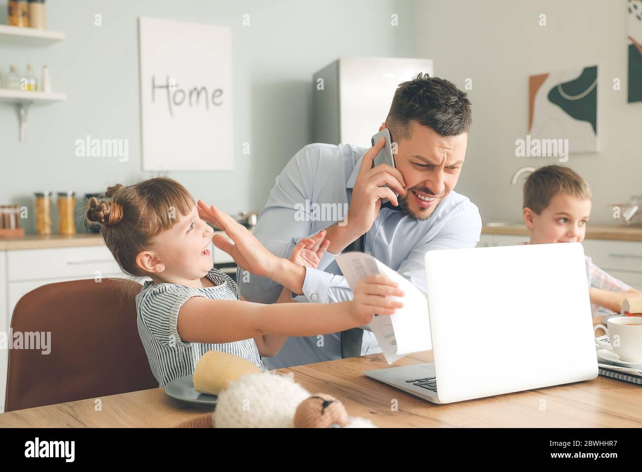 Little children keeping father from his work at home Stock Photo - Alamy