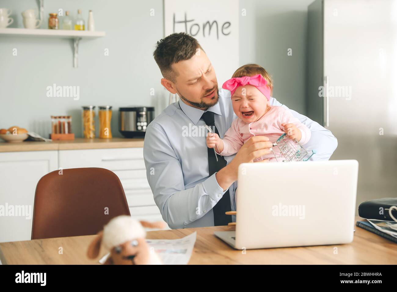 Working father with crying little daughter at home Stock Photo - Alamy