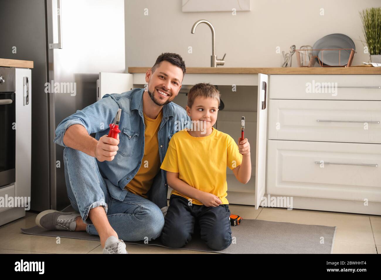 Little son helping his father to repair sink in kitchen Stock Photo - Alamy
