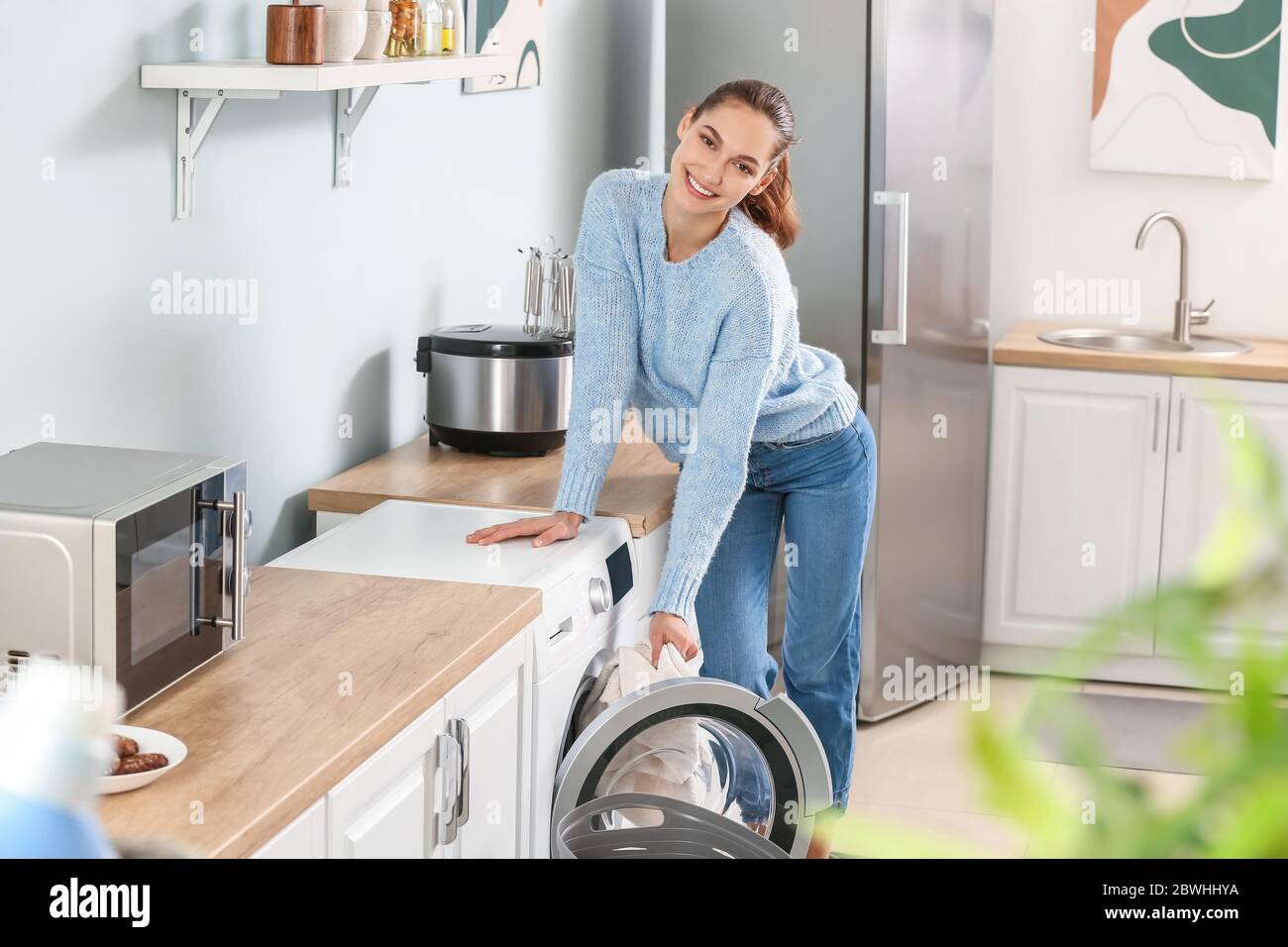 Young woman doing laundry at home Stock Photo - Alamy