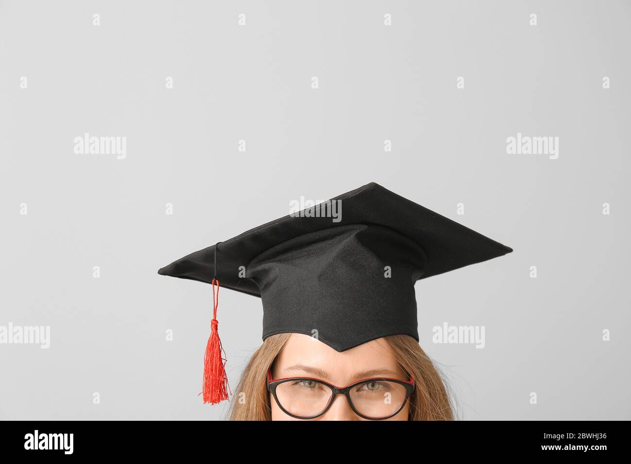 Female student in graduation hat on light background Stock Photo - Alamy