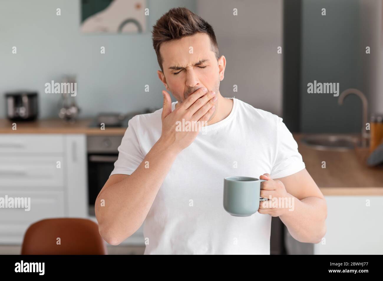 Sleepy man drinking coffee in kitchen Stock Photo - Alamy