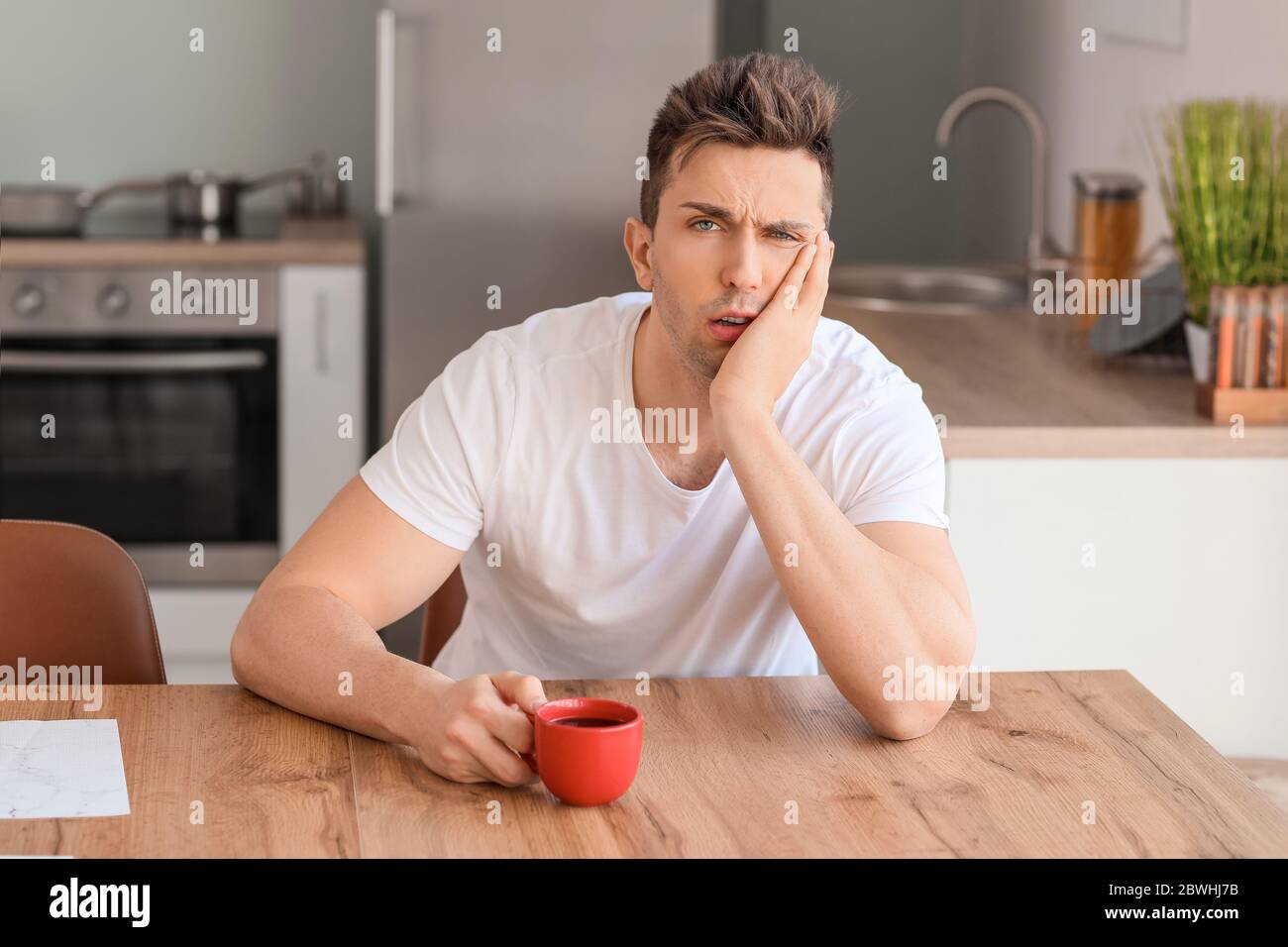 Sleepy man drinking coffee in kitchen Stock Photo - Alamy