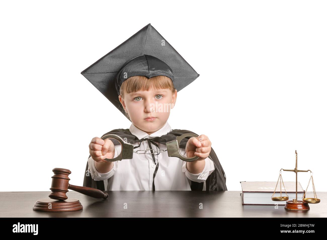 Portrait of little judge sitting at table against white background ...