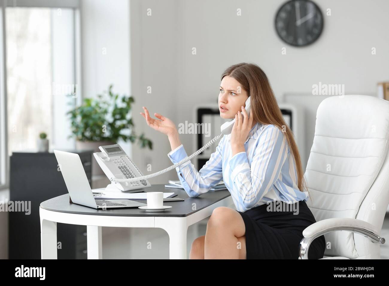 Beautiful young secretary talking by telephone while working in office ...
