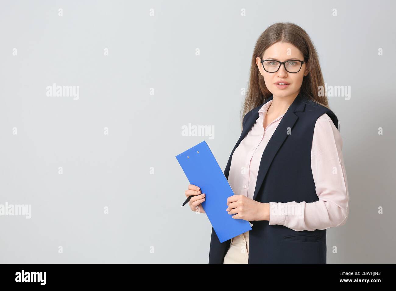 Beautiful young secretary on light background Stock Photo - Alamy