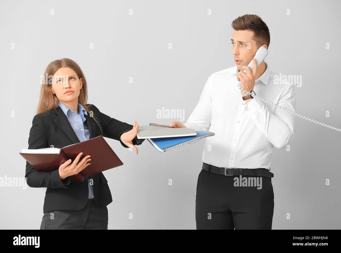 Male secretary and his busy boss on light background Stock Photo - Alamy