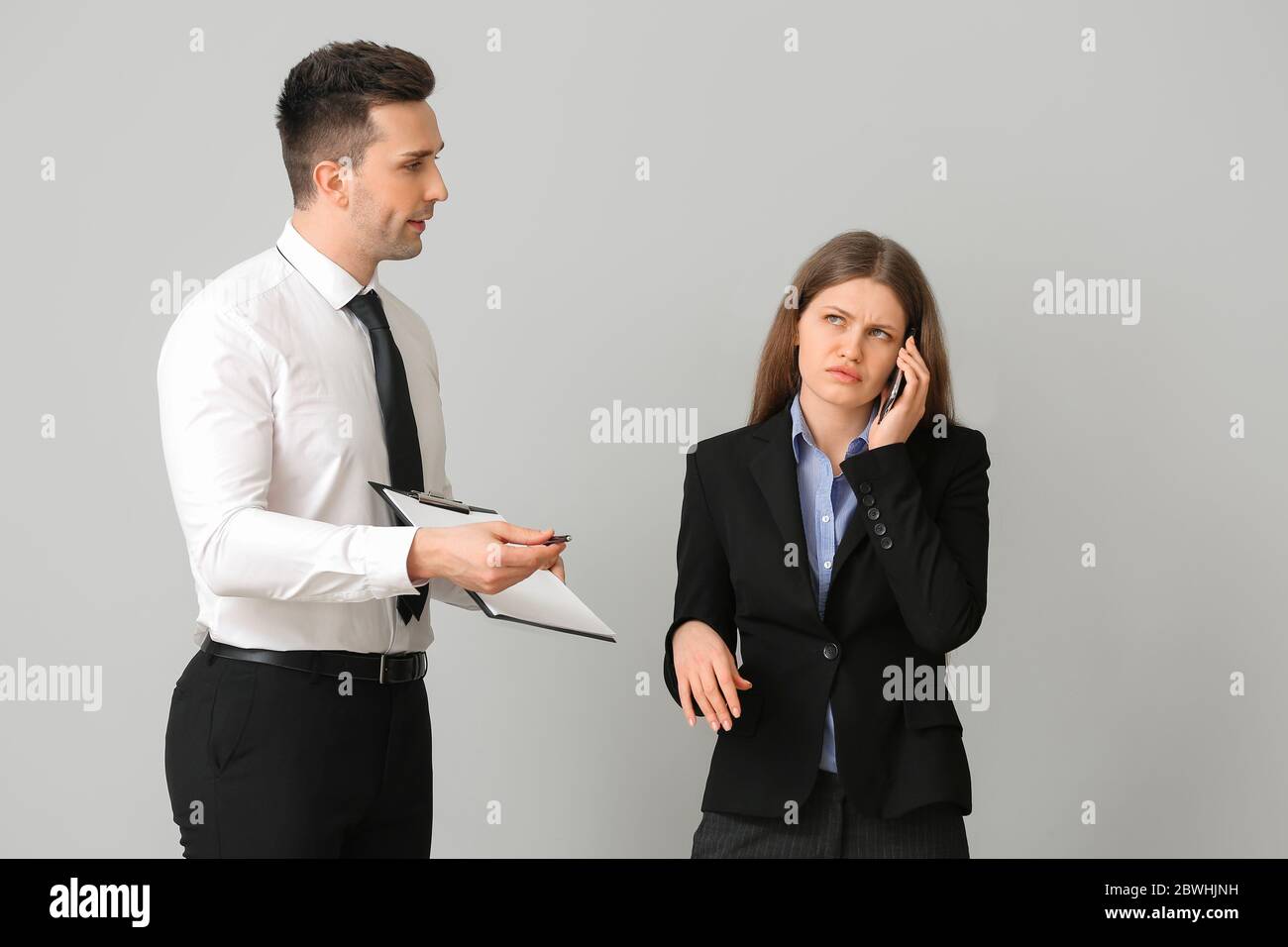 Male secretary and his busy boss on light background Stock Photo - Alamy