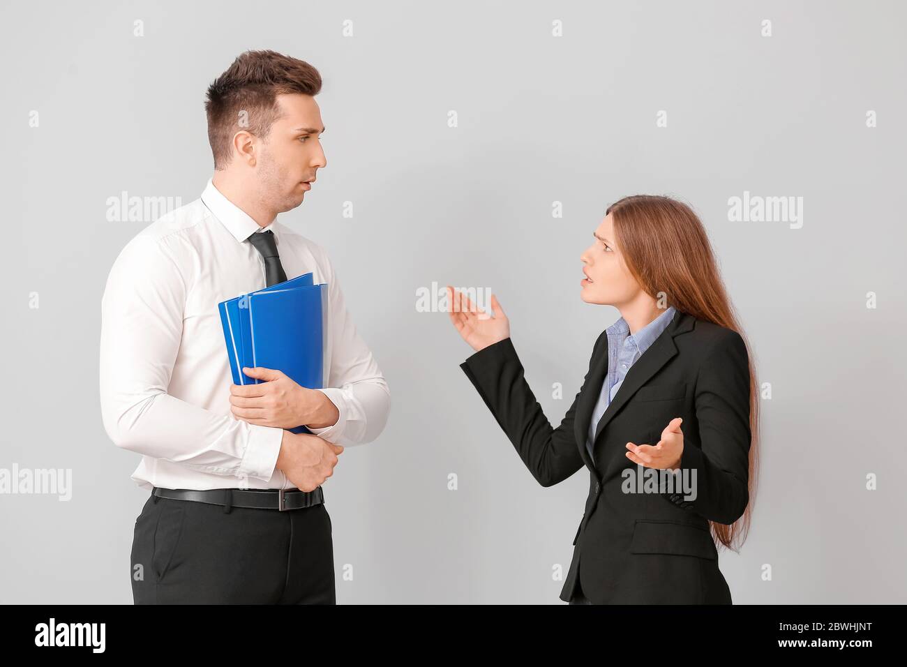 Angry female boss scolding her male secretary on light background Stock ...