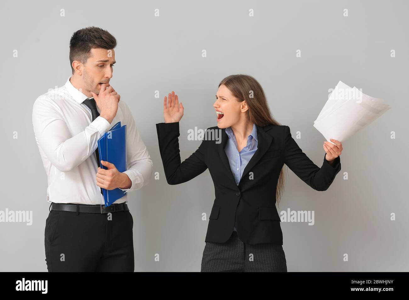 Angry female boss scolding her male secretary on light background Stock ...