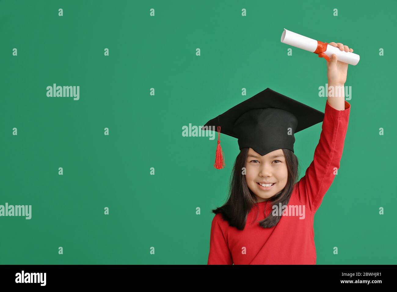 Little girl in graduation hat and with diploma on color background ...