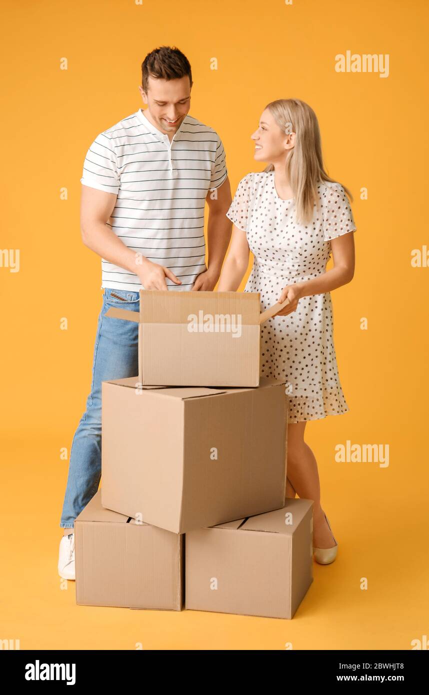 Young couple unpacking things on color background Stock Photo - Alamy