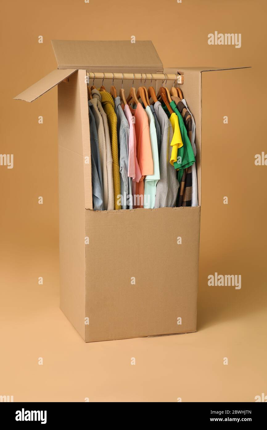 Moving box with clothes on color background Stock Photo - Alamy