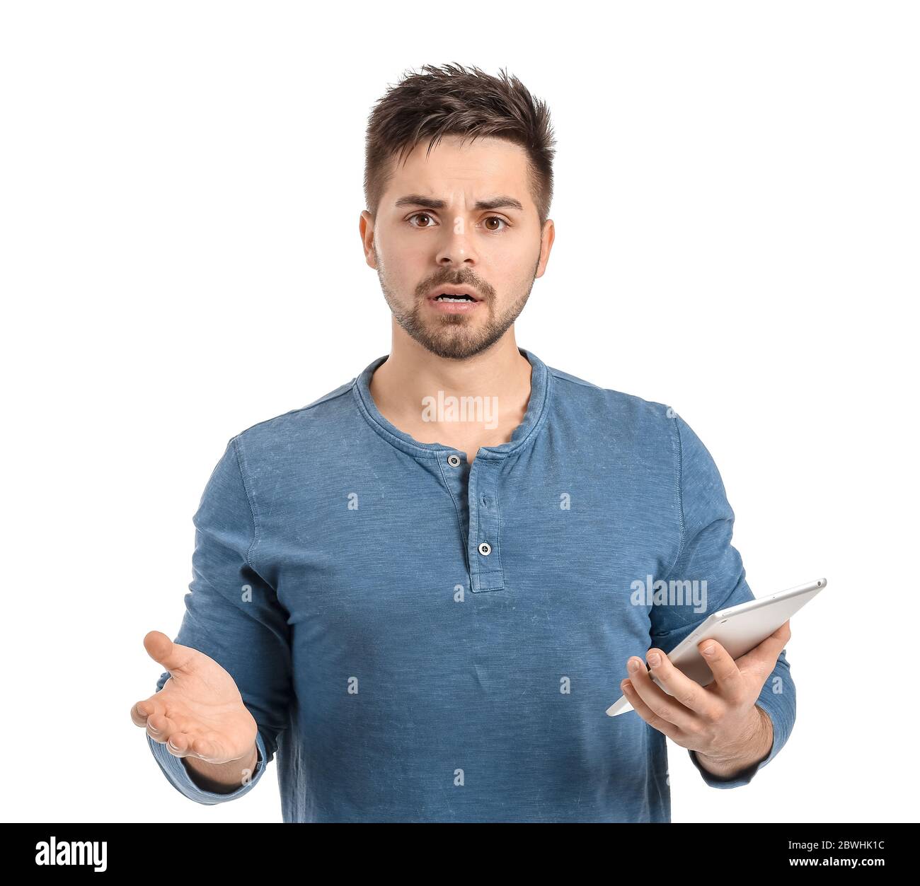 Confused young man with tablet computer on white background Stock Photo ...