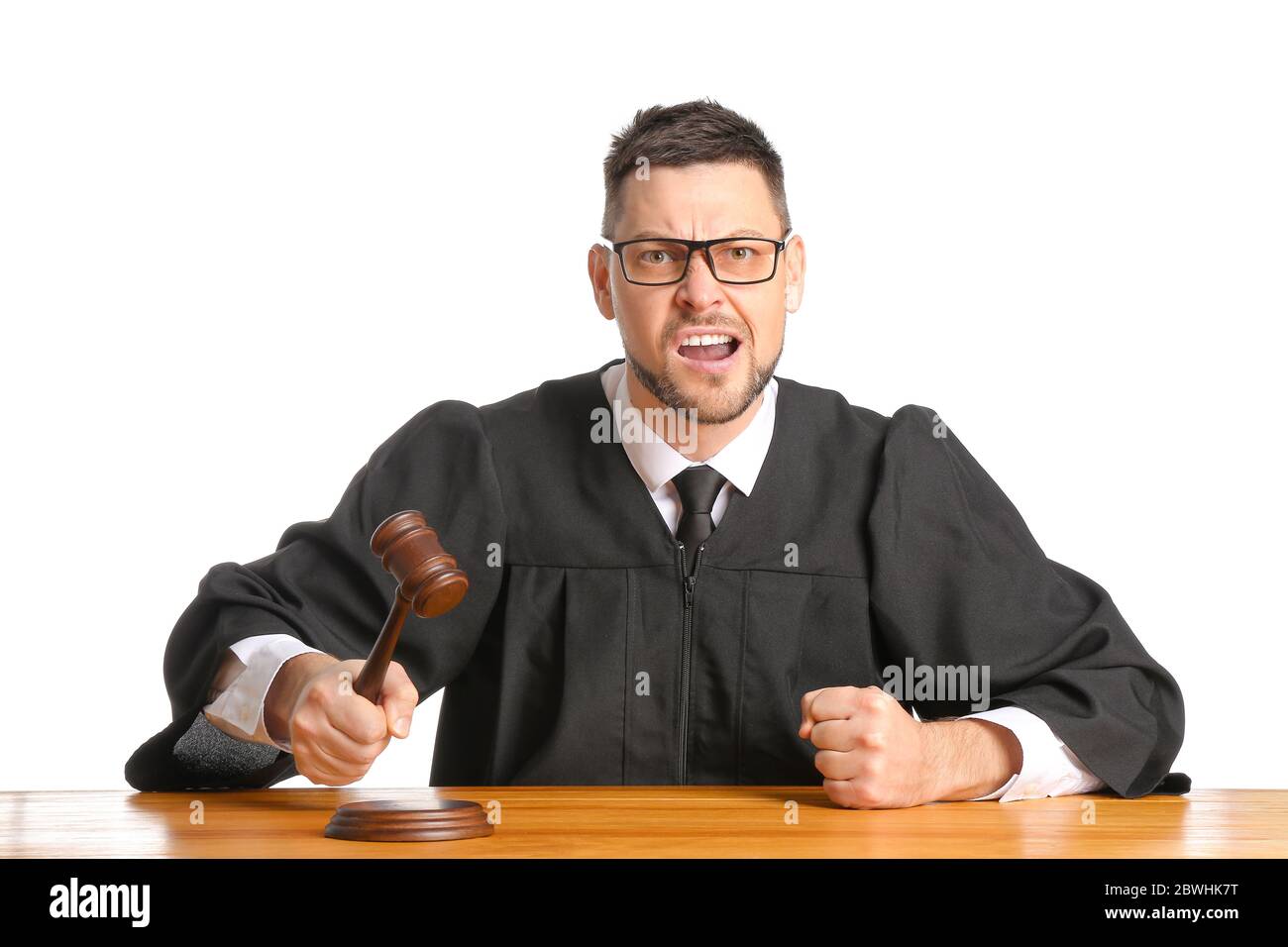 Angry male judge at table on white background Stock Photo - Alamy