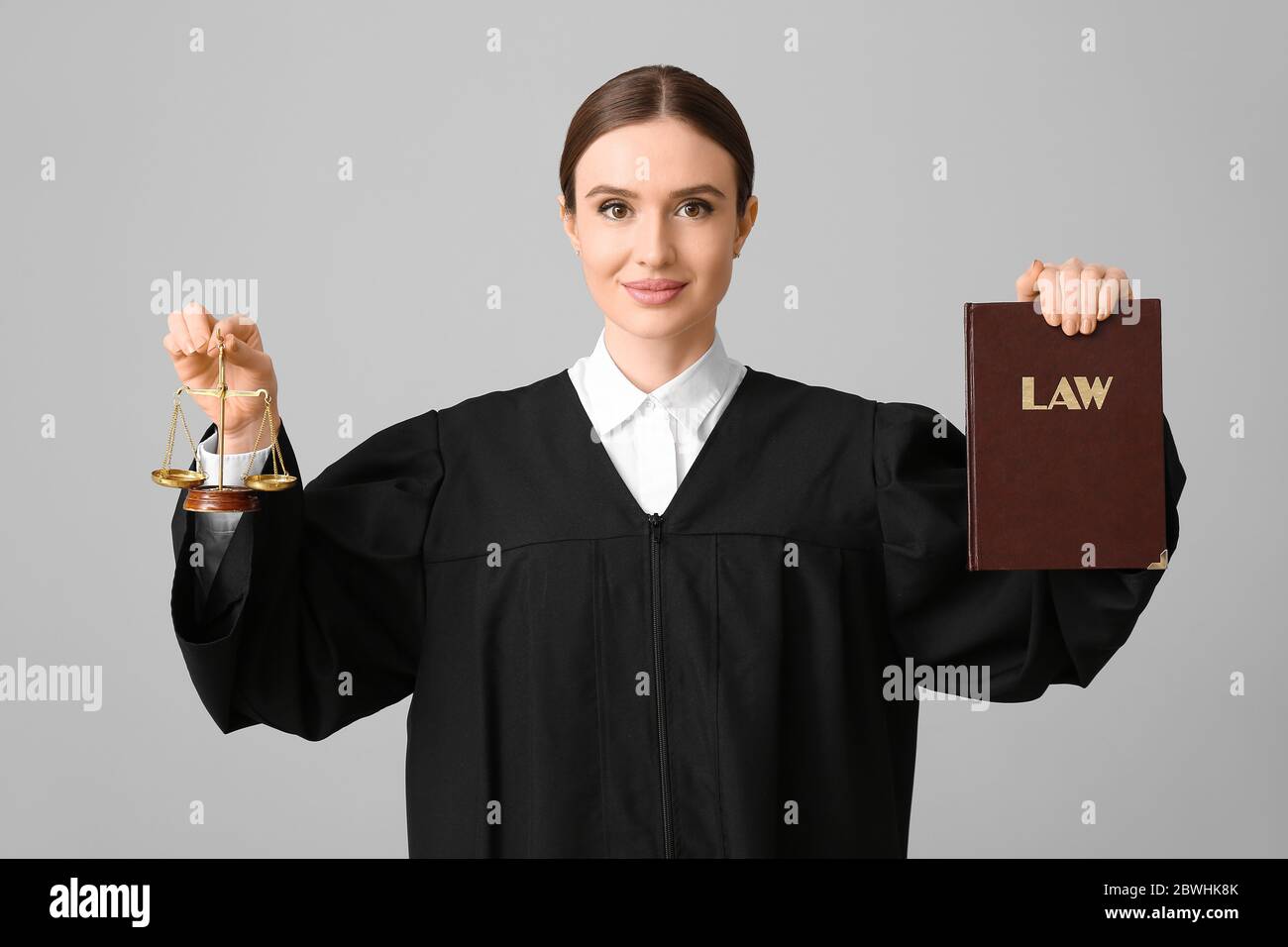 Female judge with book and scales of justice on light background Stock ...