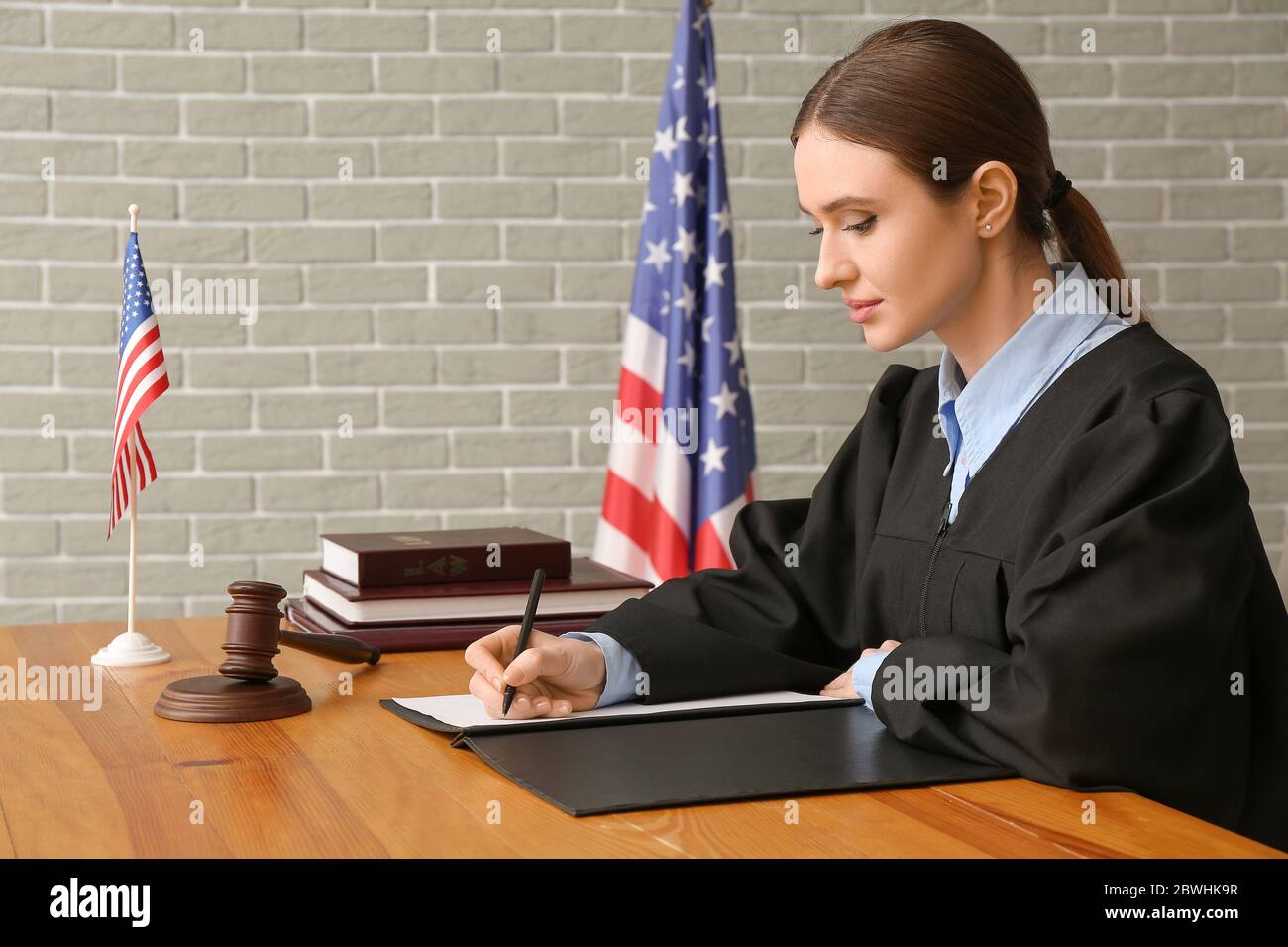 Female judge signing documents at table in courtroom Stock Photo - Alamy