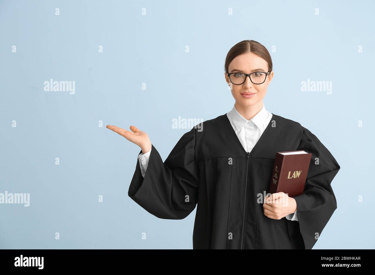 Female judge with book on light background Stock Photo - Alamy