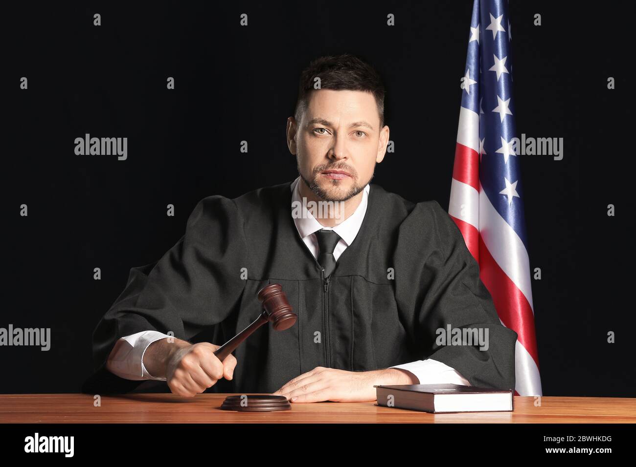Male judge at table on dark background Stock Photo - Alamy