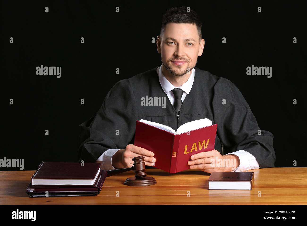 Male judge with book at table on dark background Stock Photo - Alamy