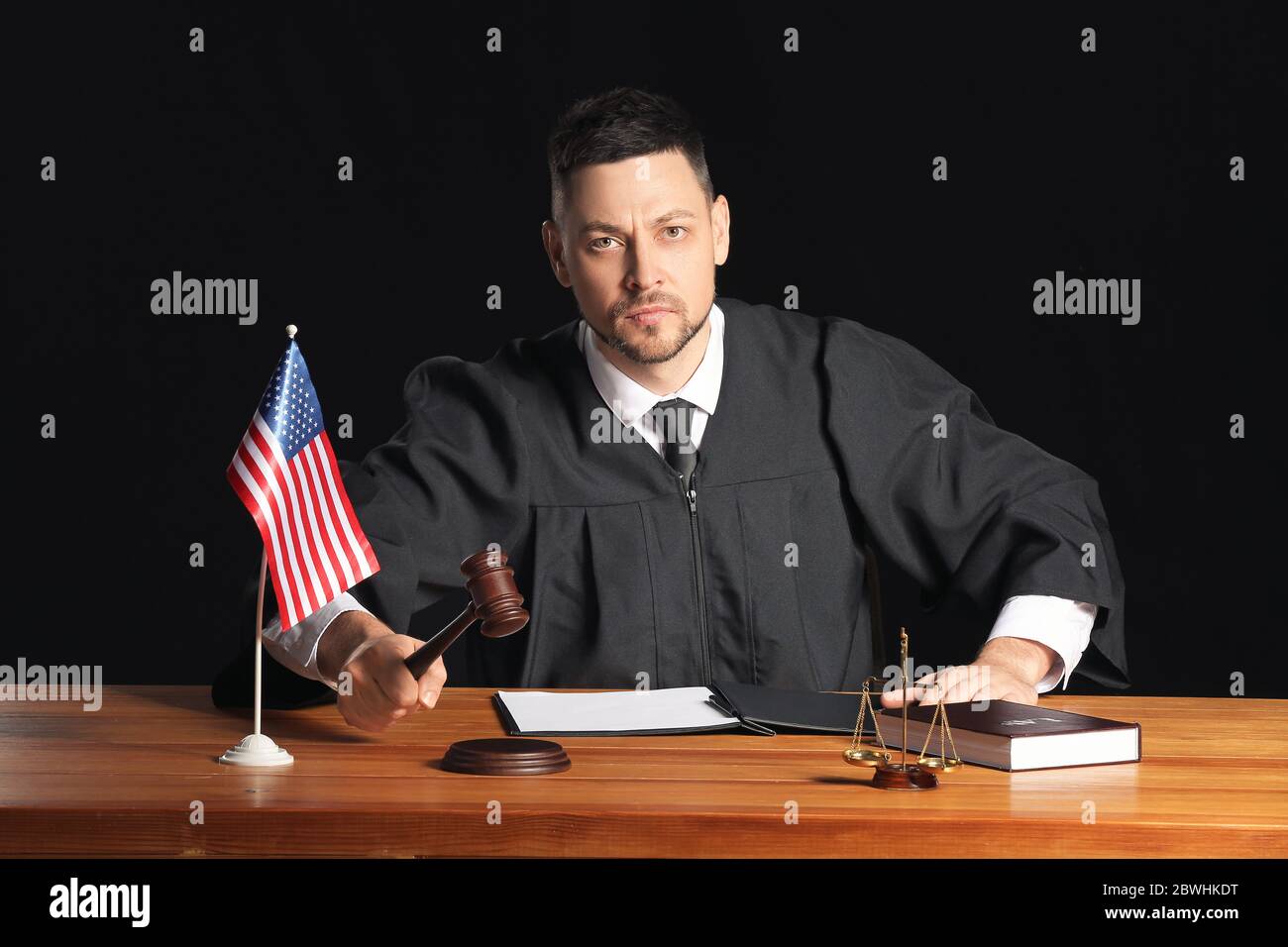 Strict male judge at table on dark background Stock Photo - Alamy