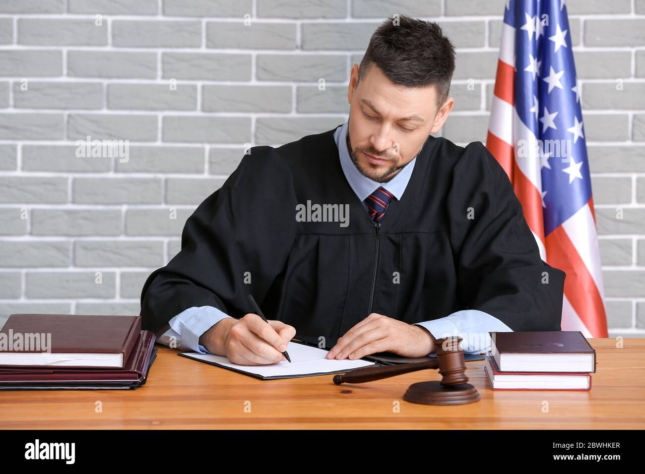 Male judge signing documents at table in courtroom Stock Photo - Alamy