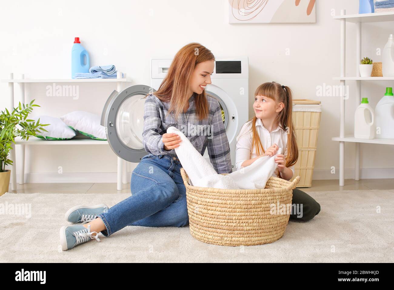 Woman and her cute little daughter doing laundry at home Stock Photo ...