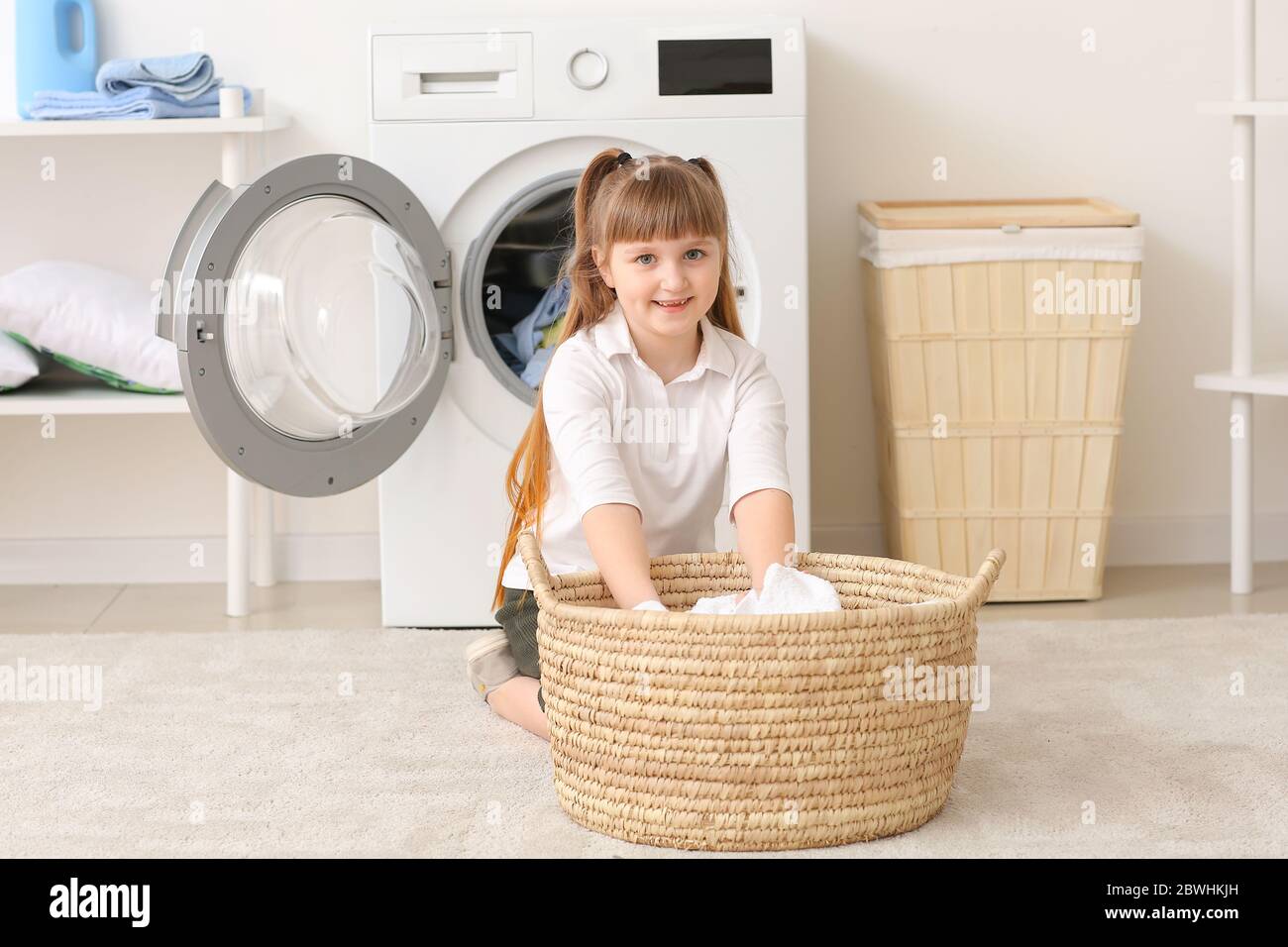 Cute little girl doing laundry at home Stock Photo - Alamy