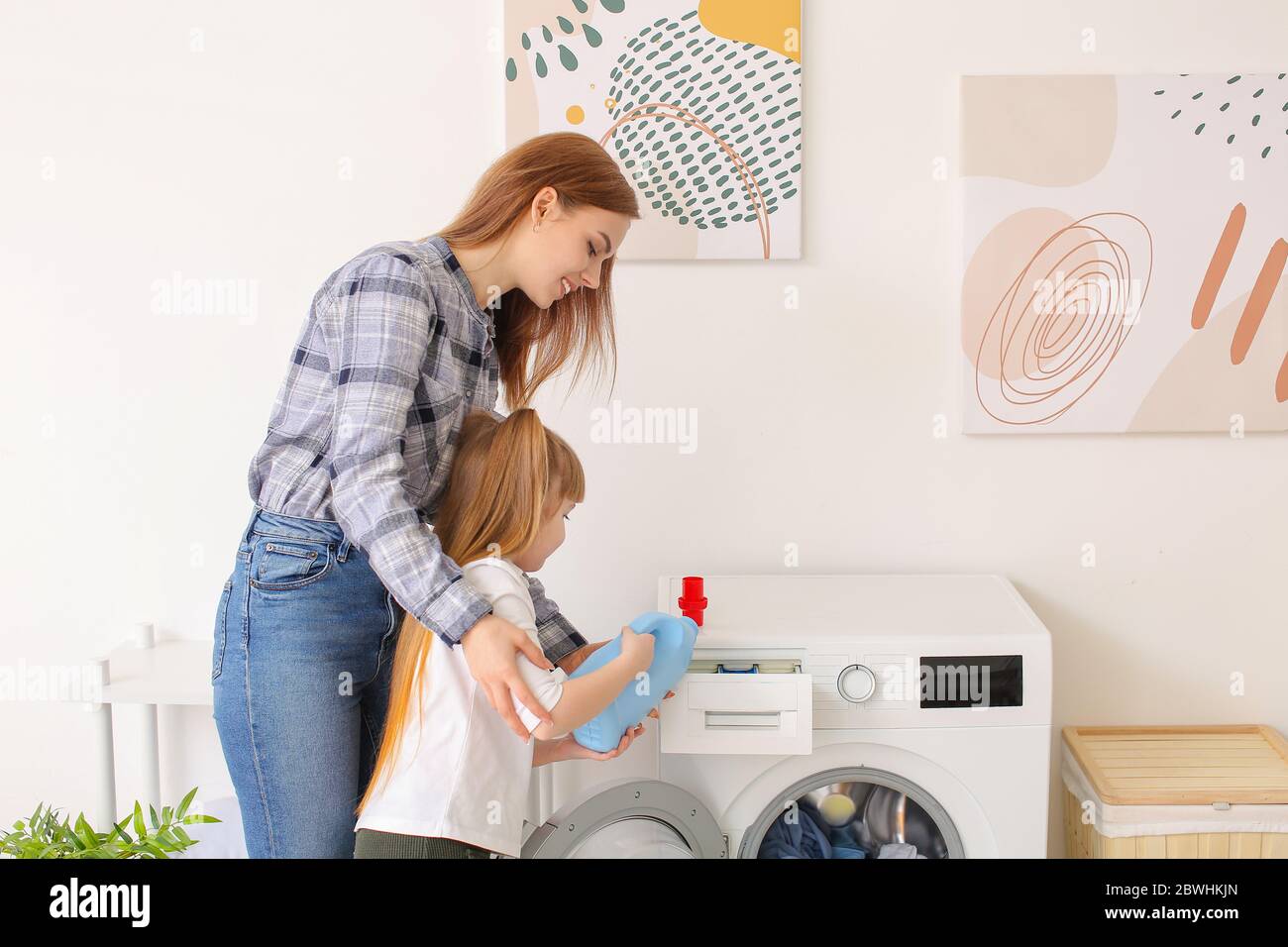 Woman and her cute little daughter doing laundry at home Stock Photo ...