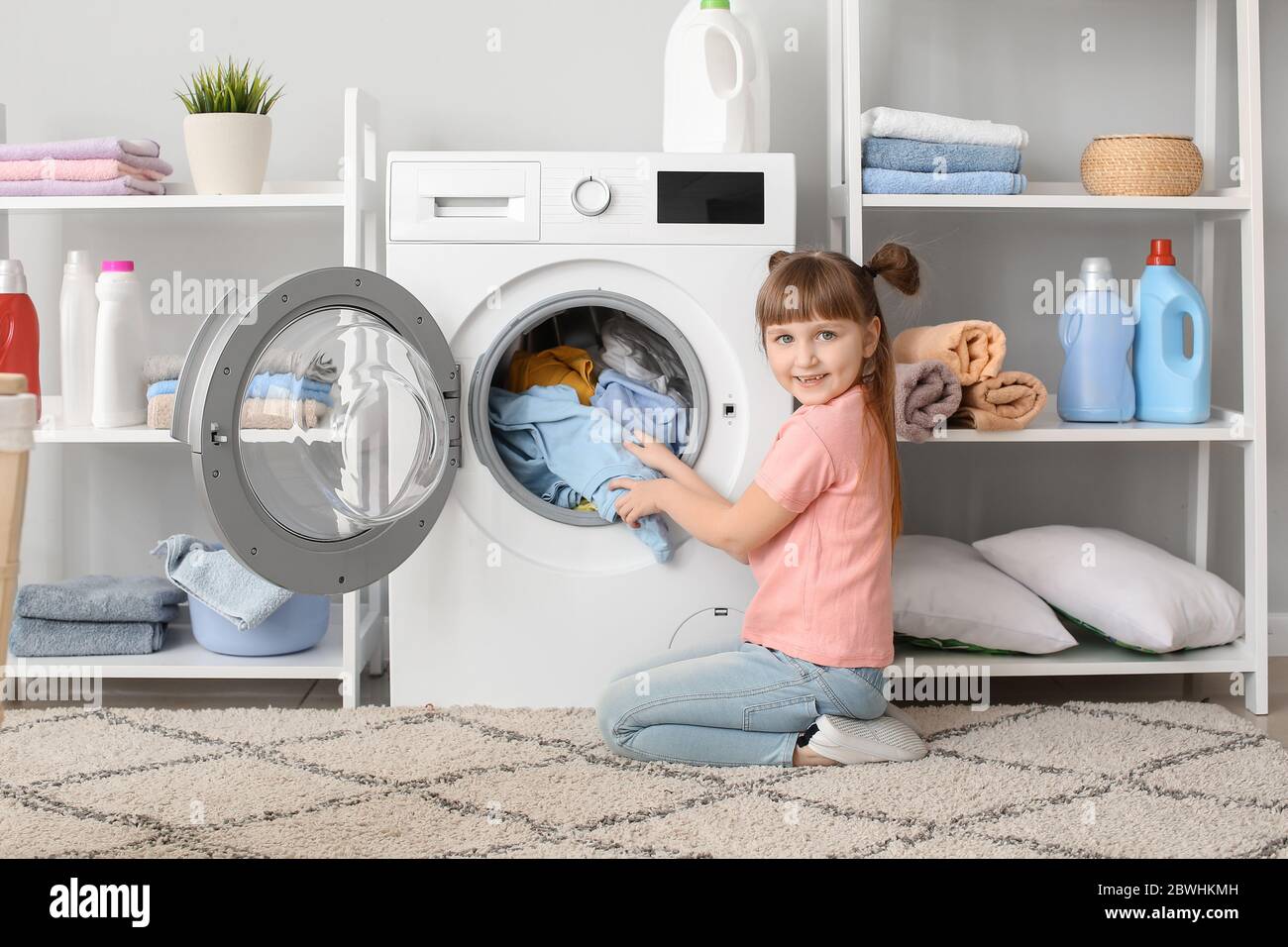 Cute little girl doing laundry at home Stock Photo - Alamy