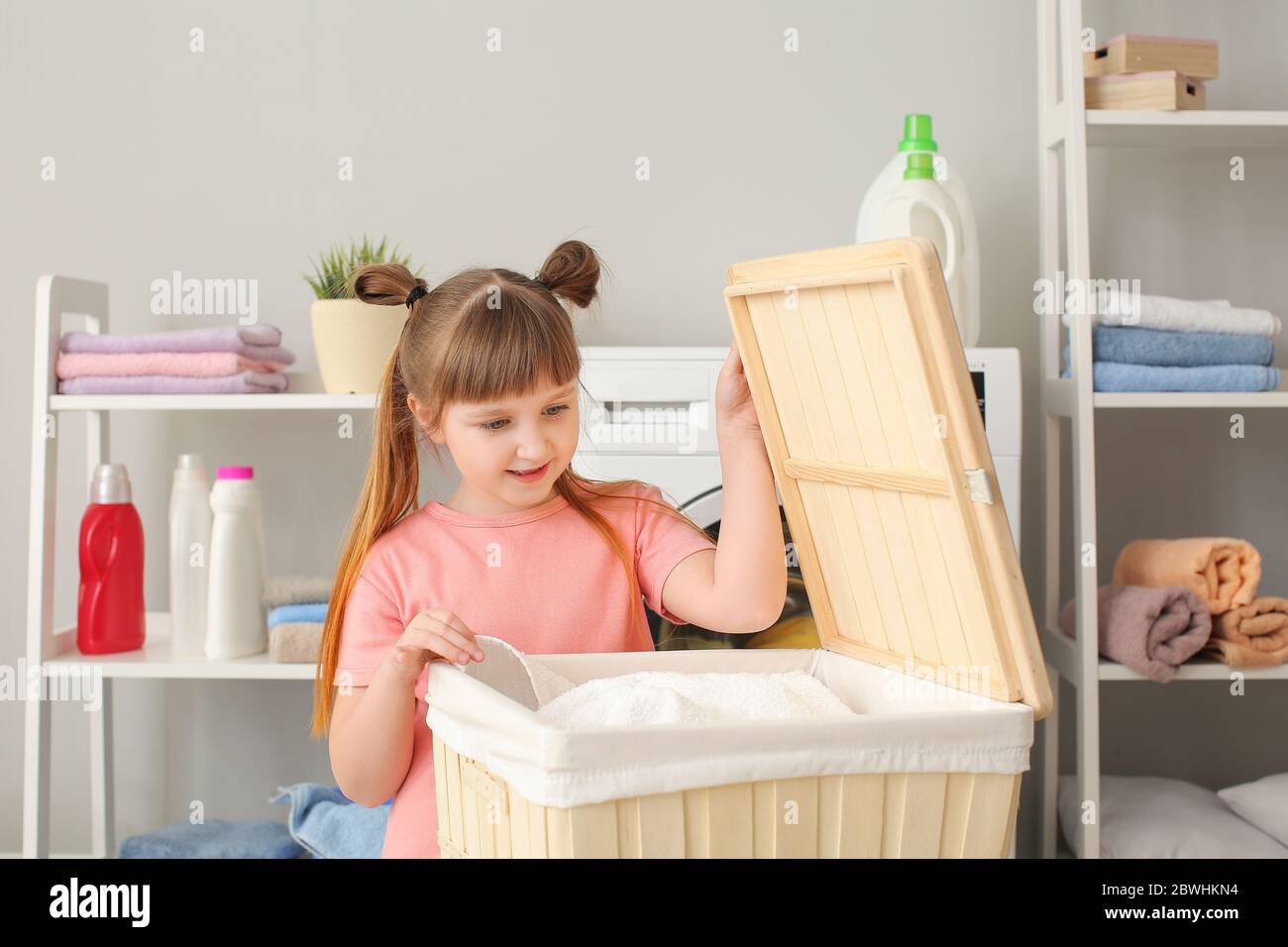 Cute little girl doing laundry at home Stock Photo - Alamy
