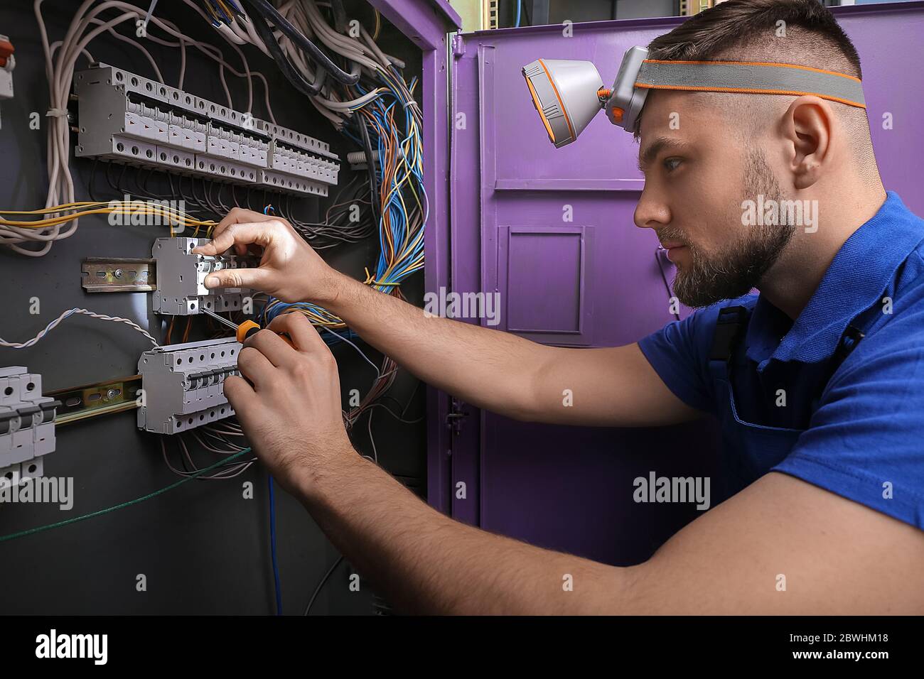 Male electrician with flashlight repairing distribution board Stock ...