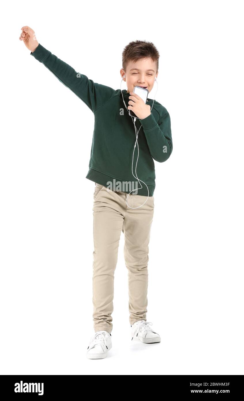 Cute little boy dancing and listening to music against white background ...