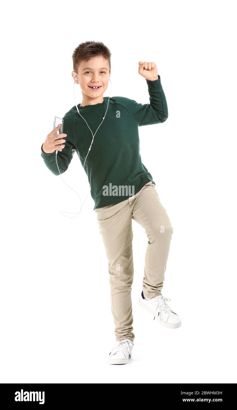 Cute little boy dancing and listening to music against white background ...