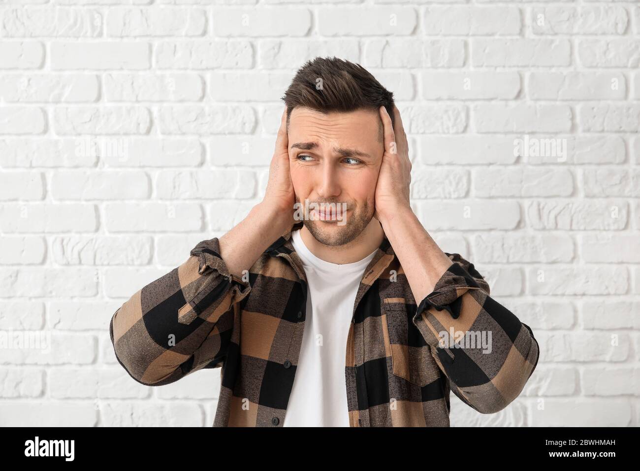 Young man suffering from loud noise on white background Stock Photo - Alamy