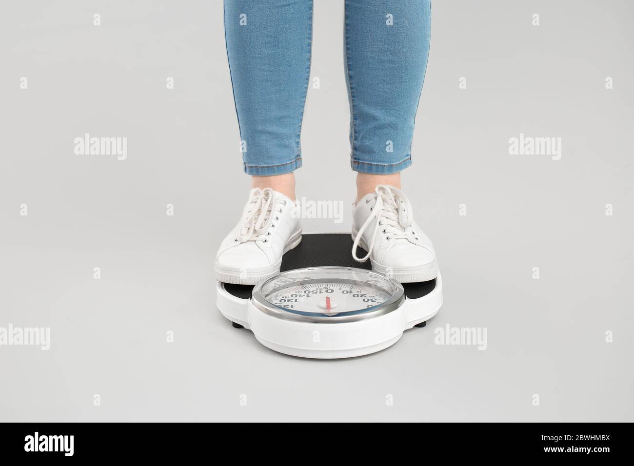 Overweight woman with scales on grey background. Weight loss concept ...