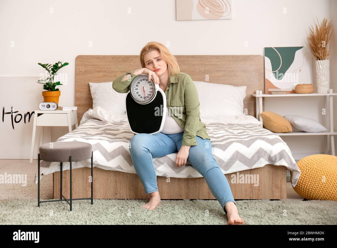 Sad overweight woman with scales at home Stock Photo - Alamy