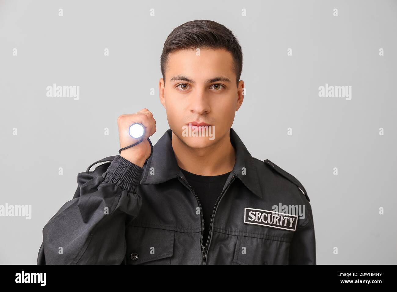 Male security guard with flashlight on grey background Stock Photo - Alamy