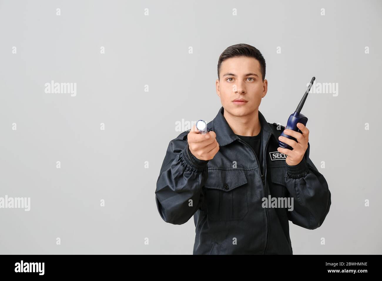 Male security guard with flashlight on grey background Stock Photo - Alamy