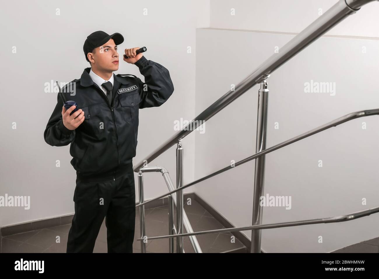 Male security guard with flashlight in building Stock Photo - Alamy
