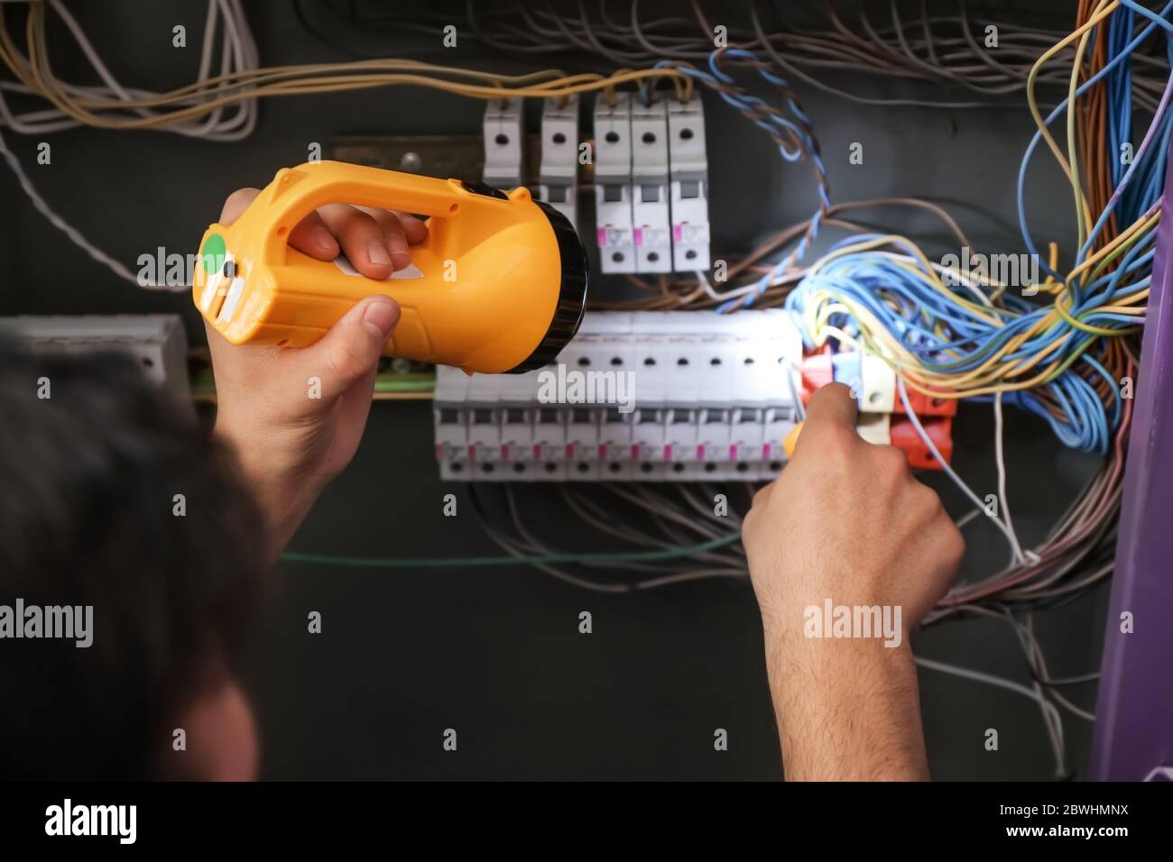 Male electrician with flashlight repairing distribution board Stock ...