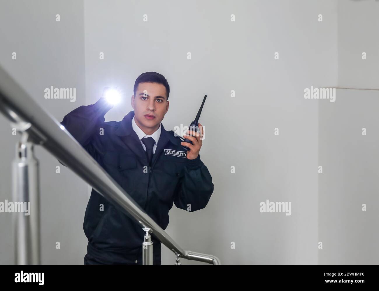 Male security guard with flashlight in building Stock Photo - Alamy