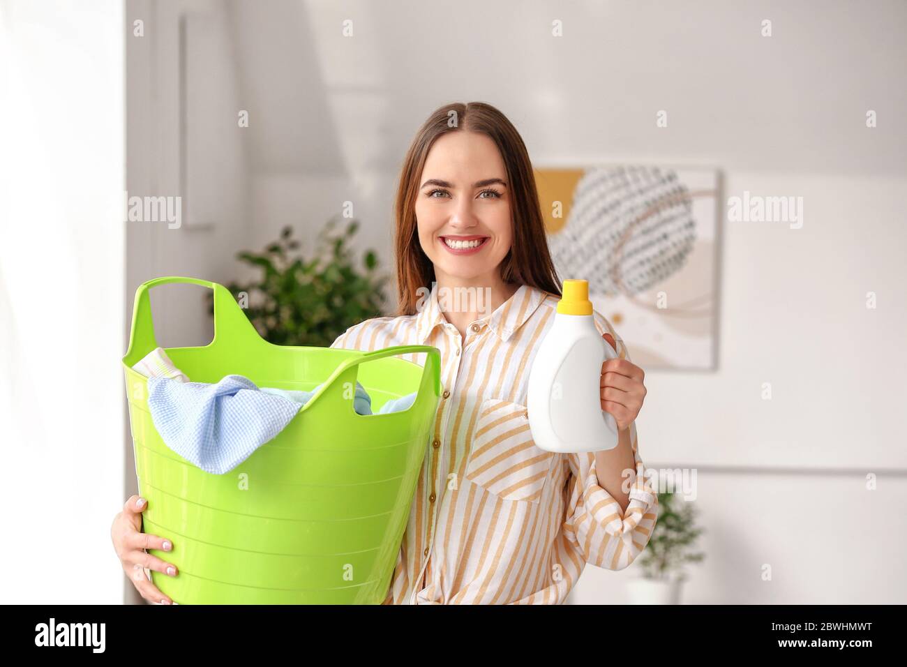 Young woman with clean laundry and detergent at home Stock Photo - Alamy
