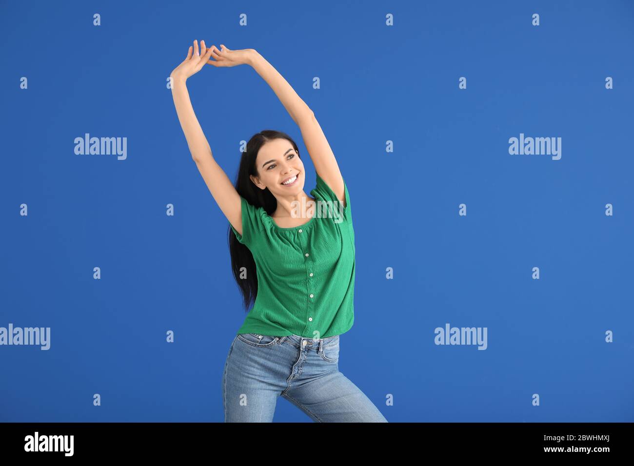 Beautiful young woman dancing against color wall Stock Photo - Alamy