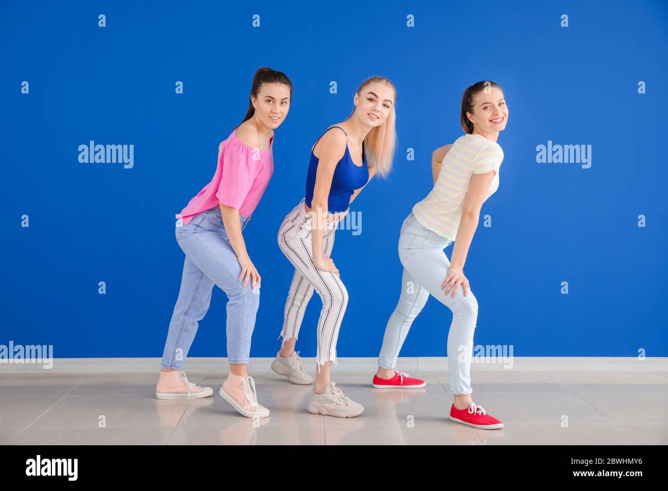 Beautiful young women dancing against color wall Stock Photo - Alamy