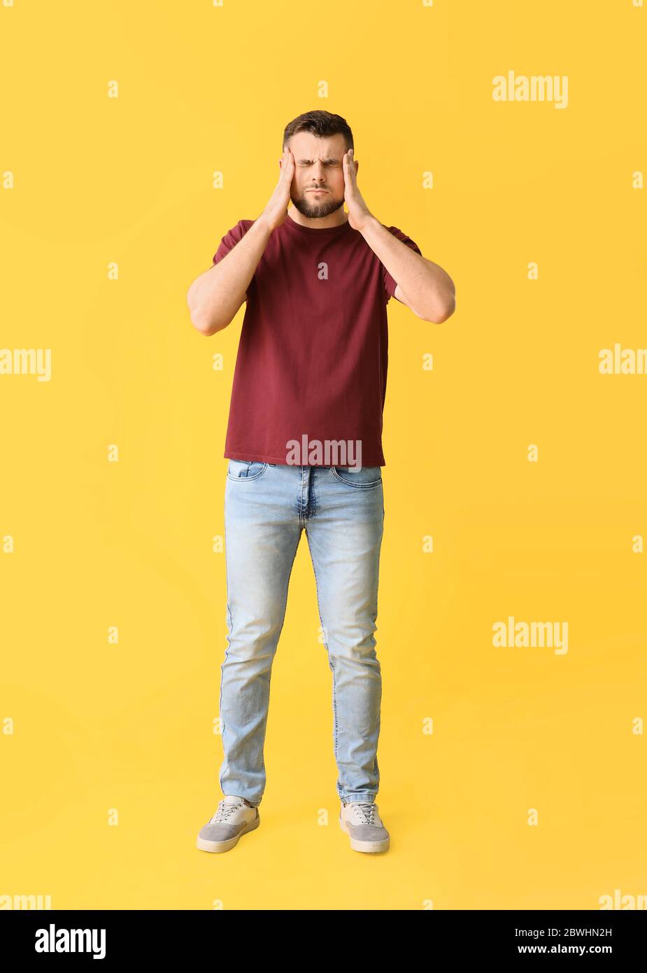 Young man suffering from loud noise on color background Stock Photo - Alamy