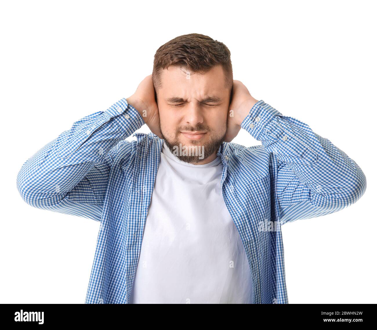 Young man suffering from loud noise on white background Stock Photo - Alamy